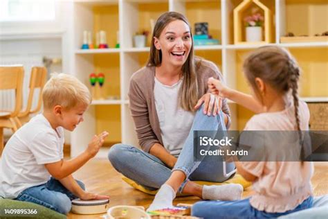 유치원 교사는 바닥에 앉아서 다양한 악기와 타악기를 사용하여 음악 수업을 듣는 아이들 교사 교육 관련 직업에 대한 스톡 사진 및 기타 이미지 교사 교육 관련 직업 어린
