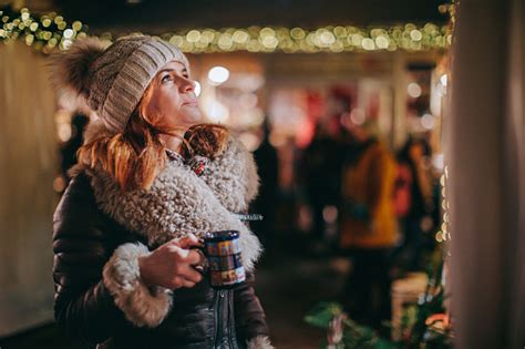 따뜻한 옷을 입은 여자는 크리스마스 시간에 뜨거운 음료수 머그잔을 들고 야외에 서 있다 강림절에 대한 스톡 사진 및 기타 이미지 강림절 여자 겨울 Istock