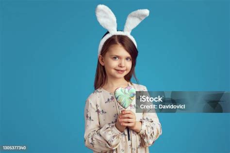 사랑스러운 매력적인 소녀 들고 A 쿠키 모양의 마음 입고 토끼 귀 위에 블루 벽 8 9 살에 대한 스톡 사진 및 기타 이미지