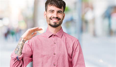 잘생긴 젊은이 손으로 크고 큰 크기 표시 측정 기호를 보여주는 몸짓 격리 된 배경 위에 분홍색 셔츠를 입고 카메라를 보고 웃 고 측정 개념입니다 개념에 대한 스톡 사진 및