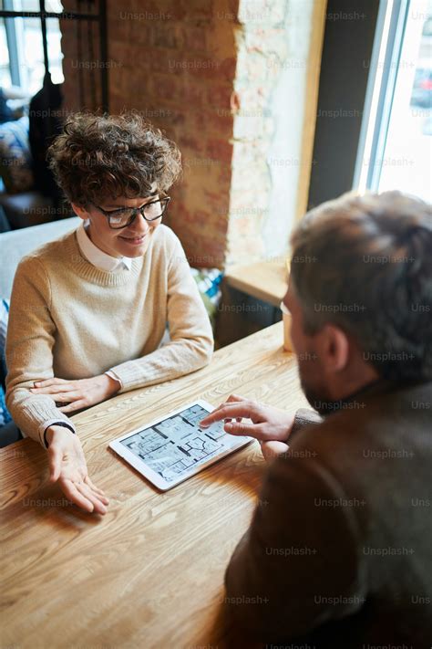 작업 회의에서 터치패드로 계획을 논의하는 동안 동료의 말을 듣고 있는 꽤 젊은 엔지니어 사진 Unsplash의 동료 이미지