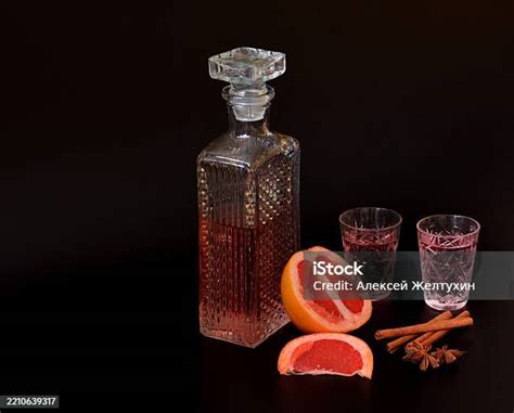 계피와 아니스를 곁들인 자몽 리큐어 검은 배경의 크리스탈 그릇에 담긴 강한 수제 알코올 잘 익은 과일과 향기로운 향신료 옆에 0