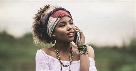 히피 라이프 스타일의 개념입니다 잔디 도로 배경에 머물고 휴대 전화로 이야기하는 미소 짓는 아프리카계 미국인 여성의 초상화를 닫습니다 사진 Unsplash의 개념 이미지