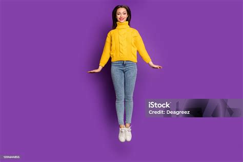 전체 길이 바디 사이즈 사진 의 쾌활 한 긍정적 인 귀여운 예쁜 여자 친구 에 청바지 데님 미소 이빨 점프 올라 고립 된 선명한 색상 배경 보라색 갈색 머리에 대한 스톡