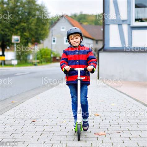 공원 자연에서 스쿠터에 타고 헬멧귀여운 작은 학교 아이 소년 겨울 봄 또는 가을에 야외 에서 활동 화려한 패션 옷에 재미 행복