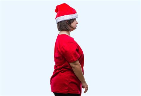 다운 증후군 입고 크리스마스 모자 사이드로 보고 격리 된 배경 위에 젊은 성인 여자 긴장 자신감 미소와 자연 스러운 얼굴 프로필
