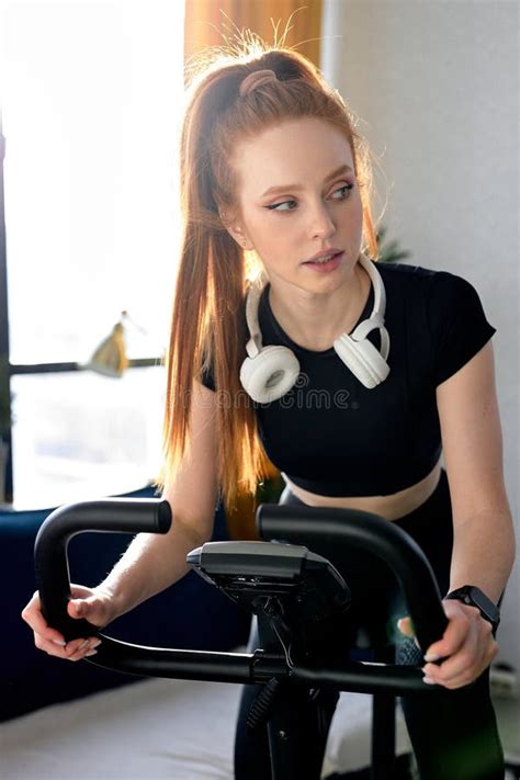 Redhead Female Working Out At Home On The Exercise Bike Young Female