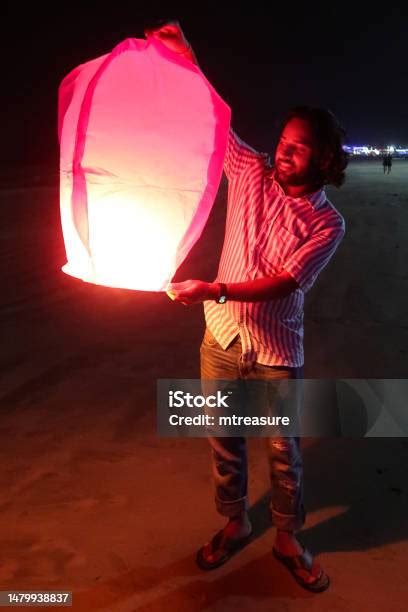 불이 켜진 종이 중국 등불을 들고 있는 인도 남자의 클로즈업 이미지 바다 옆에서 종이 등불을 풀어놓고 전경에 초점을 맞춘다 랜턴에 대한 스톡 사진 및 기타 이미지 Istock