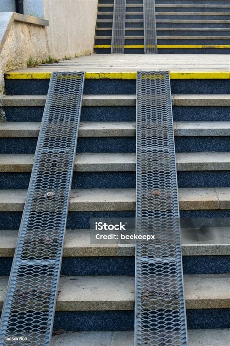 회색 콘크리트 계단과 휠체어 용으로 특별히 개조 된 난간과 결합 된 경사로 도시 공원에 들어가기위한 보안 세련된 솔루션 판금 레일 유모차 어머니 바퀴 휠체어 경사로 경사로에