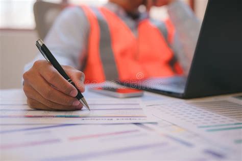 An Engineer Or Foreman Working On Site Sitting On Desk In Office Using