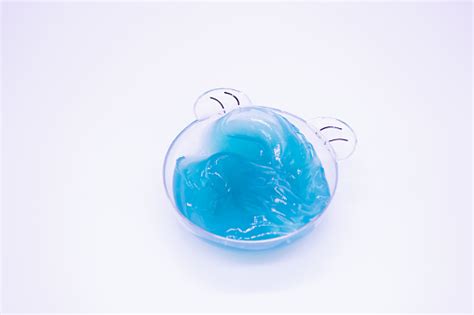 흰색 배경에 밝은 파란색 점액이있는 모양 Ob 곰 머리에 투명한 플라스틱 용기를 닫습니다 점액은 분쇄 스트레칭 찢어지고 압착됩니다 0명에 대한 스톡 사진 및 기타 이미지