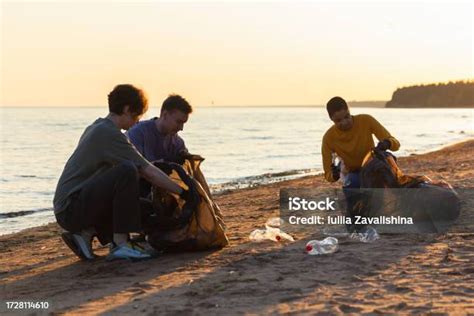 지구의 날 자원 봉사자 활동가들은 해변 해안 지역의 쓰레기 청소를 수집합니다 여자와 남자들은 바닷가에 있는 쓰레기 봉투에 플라스틱 쓰레기를 넣는다 환경 보전 해안 지역 청소