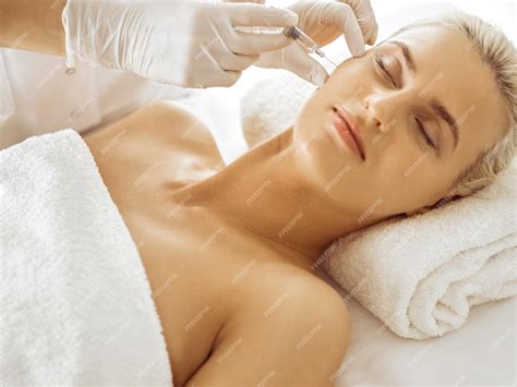 미용사 의사는 주사기로 여성의 얼굴에 미용 절차를 수행합니다 미용 의학 및 수술 미용 주사 개념 프리미엄 사진