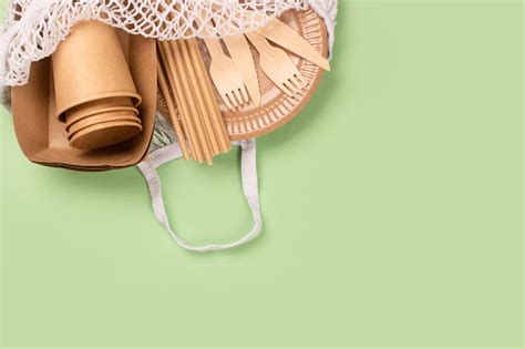 친환경 식기 복사 공간이있는 녹색 배경에 면 가방에 나무 칼이있는 크래프트 종이 식품 컵 접시 및 용기 길거리 식품 종이 포장