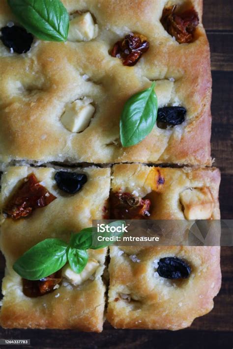 나무 도마에 슬라이스 수제 이탈리아 어 Focaccia 빵 덩어리의 이미지 녹색 올리브 햇볕에 말린 토마토와 바질 잎 장식 높은 전망페타 치즈 0명에 대한 스톡 사진 및