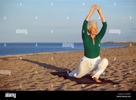 Senior Woman Practicing Yoga Poses On The Sandy Beach Elder Caucasian