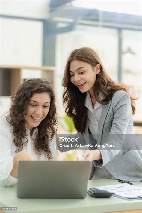 사무실에서 작업 문서를 가지고 회의 테이블에서 랩톱 컴퓨터를 사용하여 일하는 두 명의 쾌활한 사업가 부동산 프로젝트를 논의하기 위해 회의를 위한 비즈니스 동료 멘토십에 대한