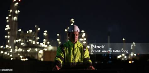 녹색 반사 안전 재킷과 흰색 헬멧을 쓴 엔지니어가 중공업 석유 화학 산업의 정유 공장 건물 구조물 앞에 서 있습니다 가솔린에