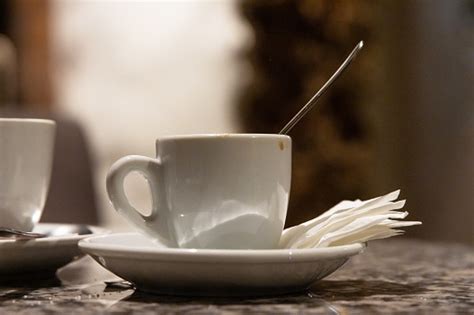 광택이 나는 화강암 표면에 숟가락과 냅킨이 놓인 미니멀한 커피 컵 은은한 조명이 켜진 카페 환경 화강암 테이블에 접시와 숟가락이 있는 클래식 화이트 에스프레소 컵 선택적