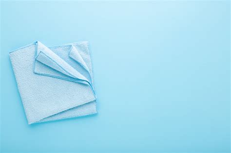 밝은 파란색 테이블 배경에서 닦는 다양한 표면을 위한 접힌 마른 부드러운 극세사 걸레 파스텔 색상 근접 촬영 텍스트를위한 빈 장소 하향식 보기 부드러움에 대한 스톡 사진 및