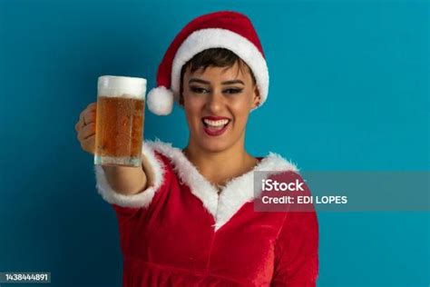 산타클로스 복장과 모자를 쓴 젊은 여성 파란색 배경과 크리스마스 테마가 있는 스튜디오 사진 12월에 대한 스톡 사진 및 기타