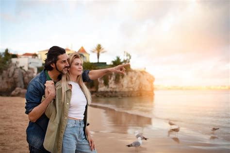 Hermosa pareja joven disfrutando de la vista del atardecer mientras está de pie en la playa