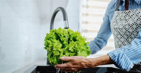 앞치마를 입은 백인 노인 여성이 부엌에 서서 부엌 싱크대에서 그린 샐러드를 씻고 있습니다 사진 Unsplash의 실내 이미지