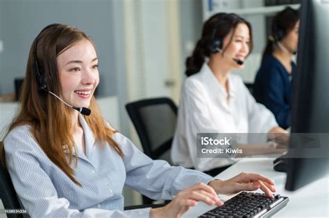 아름다운 비즈니스 여성 콜 센터 그룹의 사무실 기업에서 일합니다 매력적인 젊은 직원 근로자 사람들은 테이블에 앉아 헤드셋을 착용하고 랩톱 컴퓨터 대화를 사용하여 직장에서