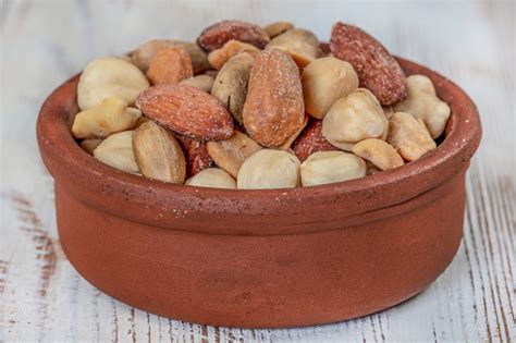 오래 된 소박한 테이블에 견과류와 말린 과일을 섞어 줍니다 골드 피스타치오 캐슈 헤이즐넛 아몬드 및 차 음식 배경입니다 0명에