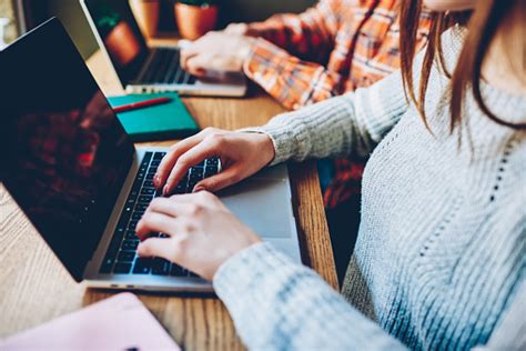 나무 바탕 화면에 앉아 무선 4g 인터넷에 연결된 현대 노트북 컴퓨터의 키보드에 텍스트 정보를 입력 여성 손의 자른 이미지 넷북에서 원격으로 작업하는 그래픽 디자이너 2명에