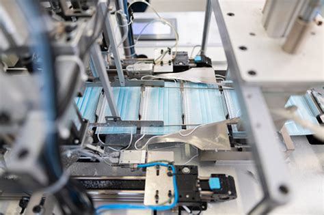 공장에서 제조되는 의료 얼굴 마스크의 클로즈업 과정 호흡기 의료 용 마스크를 대량으로 만드는 자동화 된 기계 0명에 대한 스톡