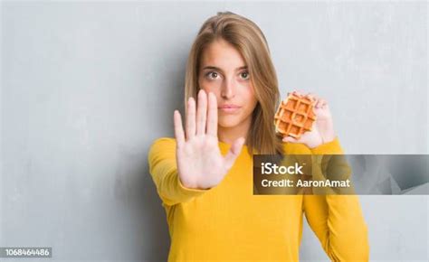 심각 하 고 자신감 표현 방어 제스처 정지 표시를 하 고 오픈 손으로 와플을 먹는 그런 지 회색 벽에 아름 다운 젊은 여자 경계 표지에 대한 스톡 사진 및 기타 이미지