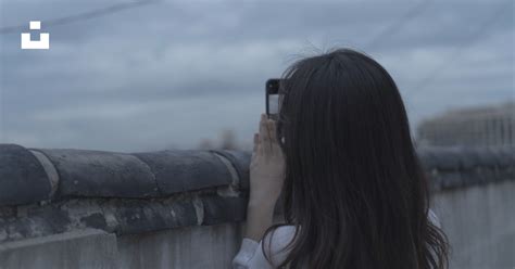 흰색 긴 소매 셔츠를 입은 여자가 검은색 스마트폰을 들고 있다 사진 Unsplash의 무료 서울 이미지