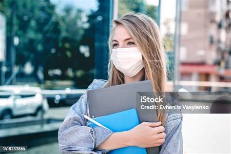 유리 비즈니스 센터의 배경에 서있는 의료 마스크를 착용 한 금발 소녀의 초상화 코로나 바이러스 격리 중 구직 활동을 클로즈업