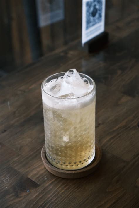 Sipper 가벼운 갈색 나무 테이블 갈증 해소 거품 거품이 많은 윗부분 고명 나무 표면 레몬에이드 레스토랑 리큐어 마시는 것 막대기 맑은 맑은