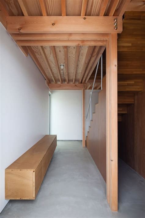An Empty Room With Wooden Beams And Stairs Leading Up To The Second Floor In Front Of A White Wall