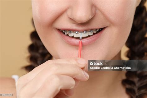 갈색 배경에 치간 브러시를 사용하여 치아를 청소하는 치과 교정기를 가진 여자 근접 촬영 25 29세에 대한 스톡 사진 및 기타 이미지 25 29세 갈색 개선 Istock
