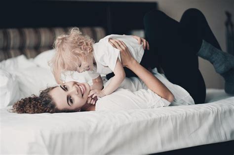 Madre Sonriente Llevando A Su Hija En La Cama En Casa Foto Premium