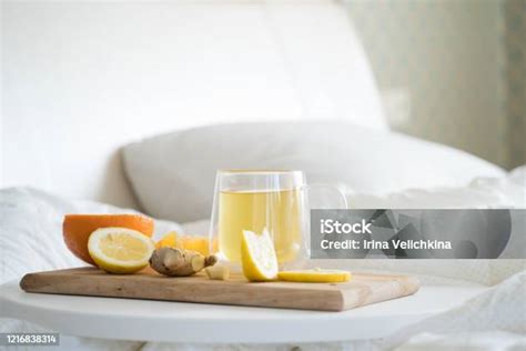 감기에 대 한 해열 제 와 컵독감 감귤류 비타민 C 생강 뿌리 레몬 오렌지와 차 환자의 침대에 나무 트레이 홈 셀프 트리트먼트