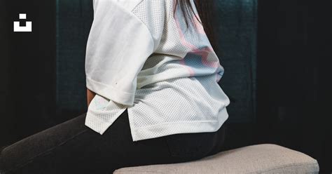 흰 셔츠와 검은 바지를 입은 사람이 갈색 의자에 앉아 있다 사진 Unsplash의 무료 무기 이미지