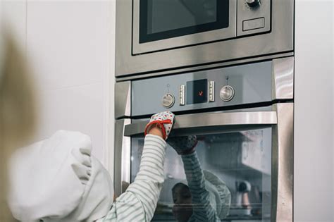 요리사 모자를 쓰고 오븐 장갑을 손에 든 금발 소년 또는 소녀가 오븐 문을 열거나 닫으려고 합니다 4 5세에 대한 스톡 사진 및 기타 이미지 Istock