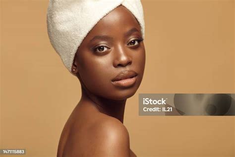 베이지색 배경에 카메라를 보고 있는 건강하고 깨끗한 피부를 가진 매력적인 아프리카 민족 여성 모델 스튜디오에서 포즈를 취하는 아름다운 검은 피부 소녀의 클로즈업 샷 한 명의