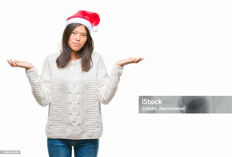 발생 하는 손과 팔으로 고립 된 배경 우 둔 하 고 혼란 스 러 워 식 이상의 크리스마스 모자를 입고 젊은 아시아 여자 의심 개념입니다 감정에 대한 스톡 사진 및 기타