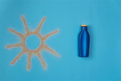 파란색 배경에 모래에 의해 그려진 태양입니다 파란색 배경에 자외선 차단제 맨 위 보기 개념에 대한 스톡 사진 및 기타 이미지 개념 노랑 메이크업 화장품 Istock