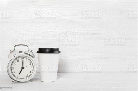 알람 시계 커피 종이컵 복사 공간이 있는 전면 보기 흰색 책상 텍스트를 위한 여유 공간이 있는 아침 배경 배너입니다 미니멀리즘 개념의 작업 공간 작업 시간 텅 빈 직장