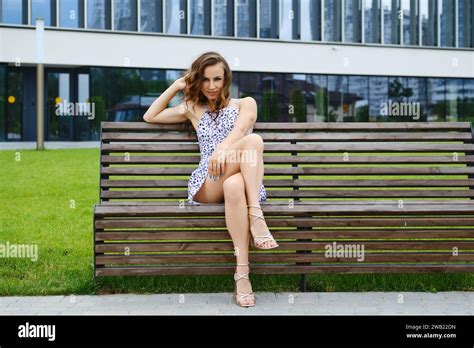 Beautiful Cute Woman Playfully Sitting On Bench Showing Her Slender