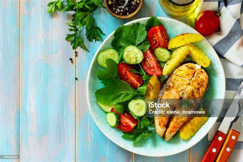 식이 요법과 건강한 영양 구운 연어 스테이크와 구운 감자 신선한 야채 샐러드를 나무 테이블에 올려놓습니다 평평한 배경의 맨 위 보기입니다 공간을 복사합니다 0명에 대한 스톡