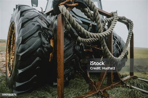 흐린 비오는 날 에 거대한 두 배 바퀴와 오래 된 버려진 트랙터의 뒷면에 후면 녹슨 프레임에 코일 및 매달려 두꺼운 젖은 로프의 세부 사항 0명에 대한 스톡 사진 및 기타