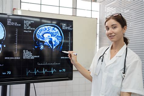 뇌 연구실에서 Mri Ct를 보여주는 모니터로 뇌 영상을 스캔하는 여성 의료진 뇌 프로젝트의 자기 공명 영상을 보여주는 유니폼을 입은 여성 의사 사람들에 대한 스톡 사진 및