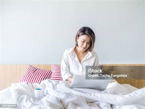 집에서 침대에 노트북 컴퓨터와 함께 작업 흰색 셔츠를 입고 짧은 머리를 가진 아름다운 아시아 여성 감정에 대한 스톡 사진 및 기타 이미지 Istock